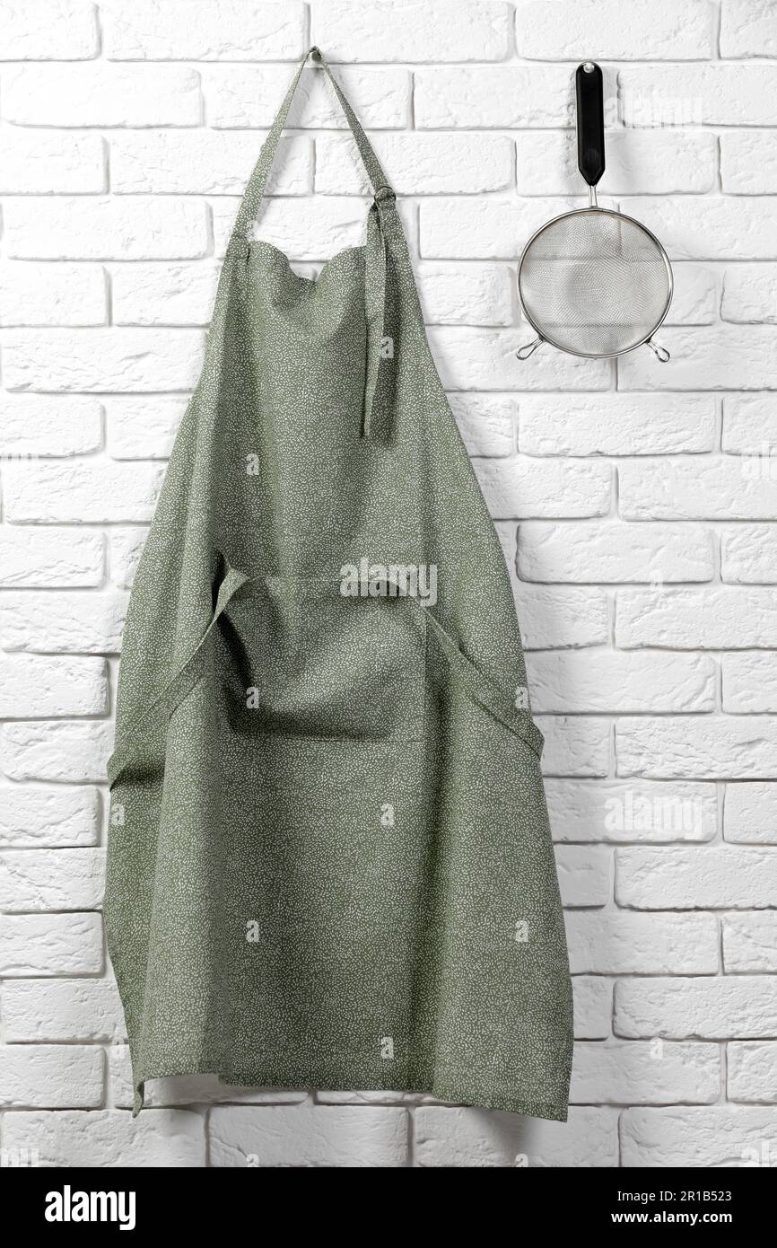 Clean kitchen apron with pattern and sieve on white brick wall Stock ...