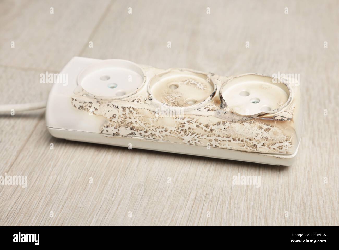 Burnt power strip on wooden floor, closeup. Electrical short circuit ...