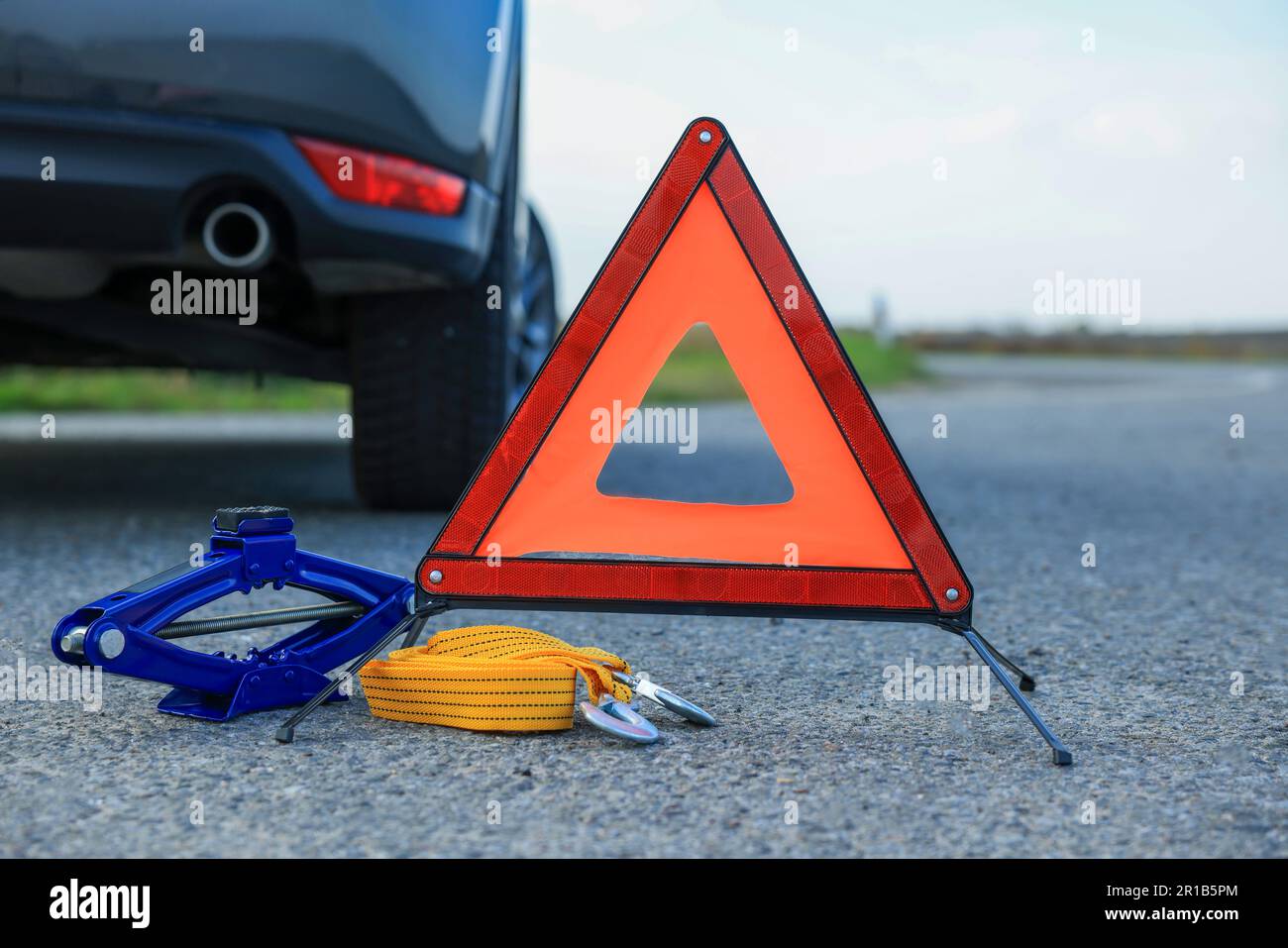 Emergency warning triangle, towing strap and scissor jack near car ...