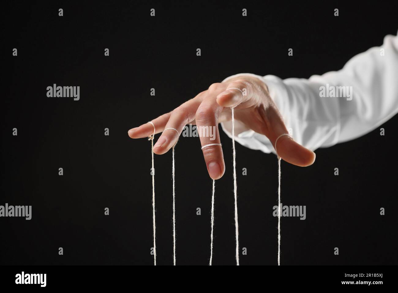 Woman pulling strings of puppet on black background, closeup Stock ...