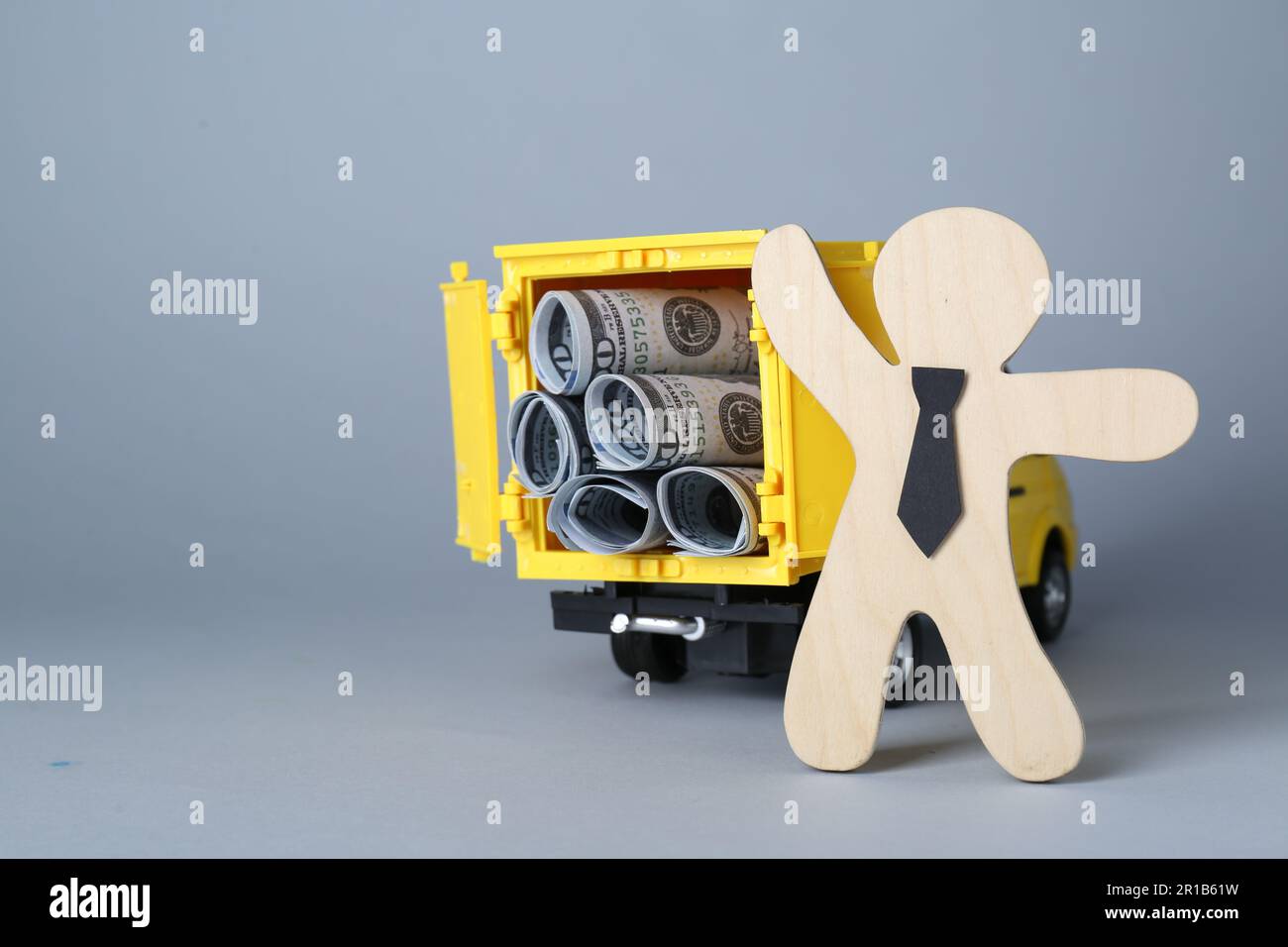 Economic profit. Wooden figure and toy truck with banknotes on light ...