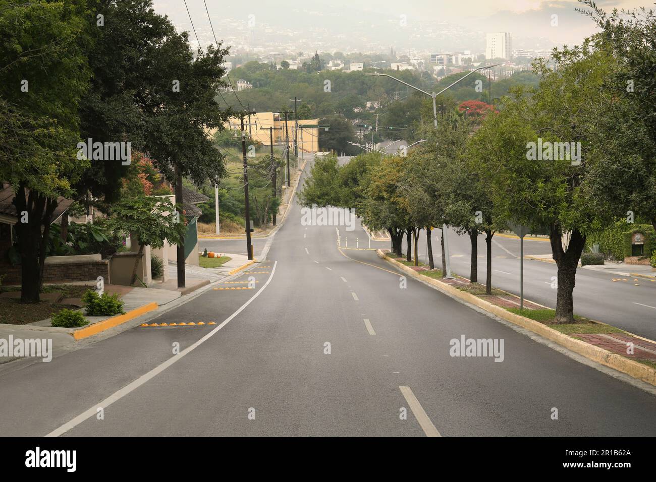 Beautiful city street with wide asphalt road and green trees Stock ...
