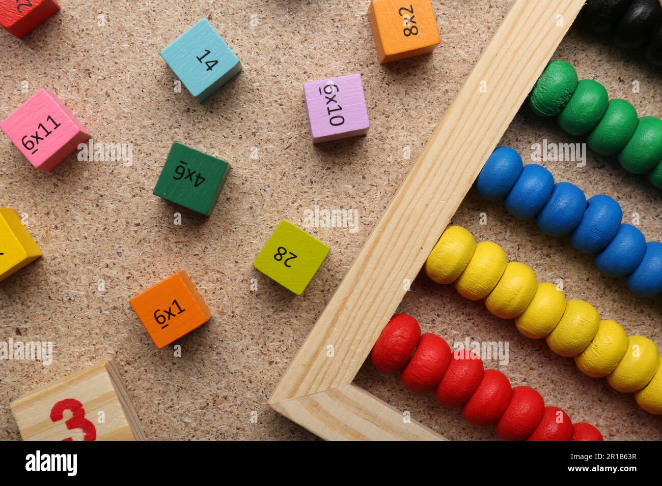 Wooden cubes with numbers and multiplications near abacus on fiberboard ...