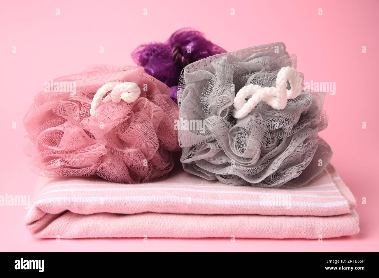 Colorful shower puffs and towel on pink background Stock Photo - Alamy