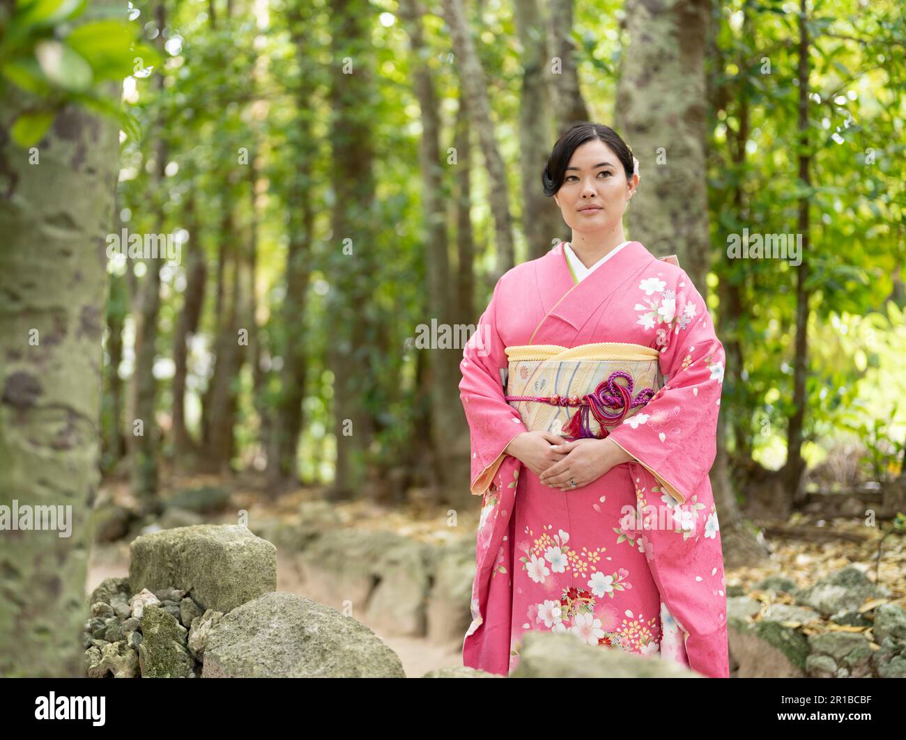 Beautiful young mixed race Japanese / American woman wearing a kimono standing on the footpath ...