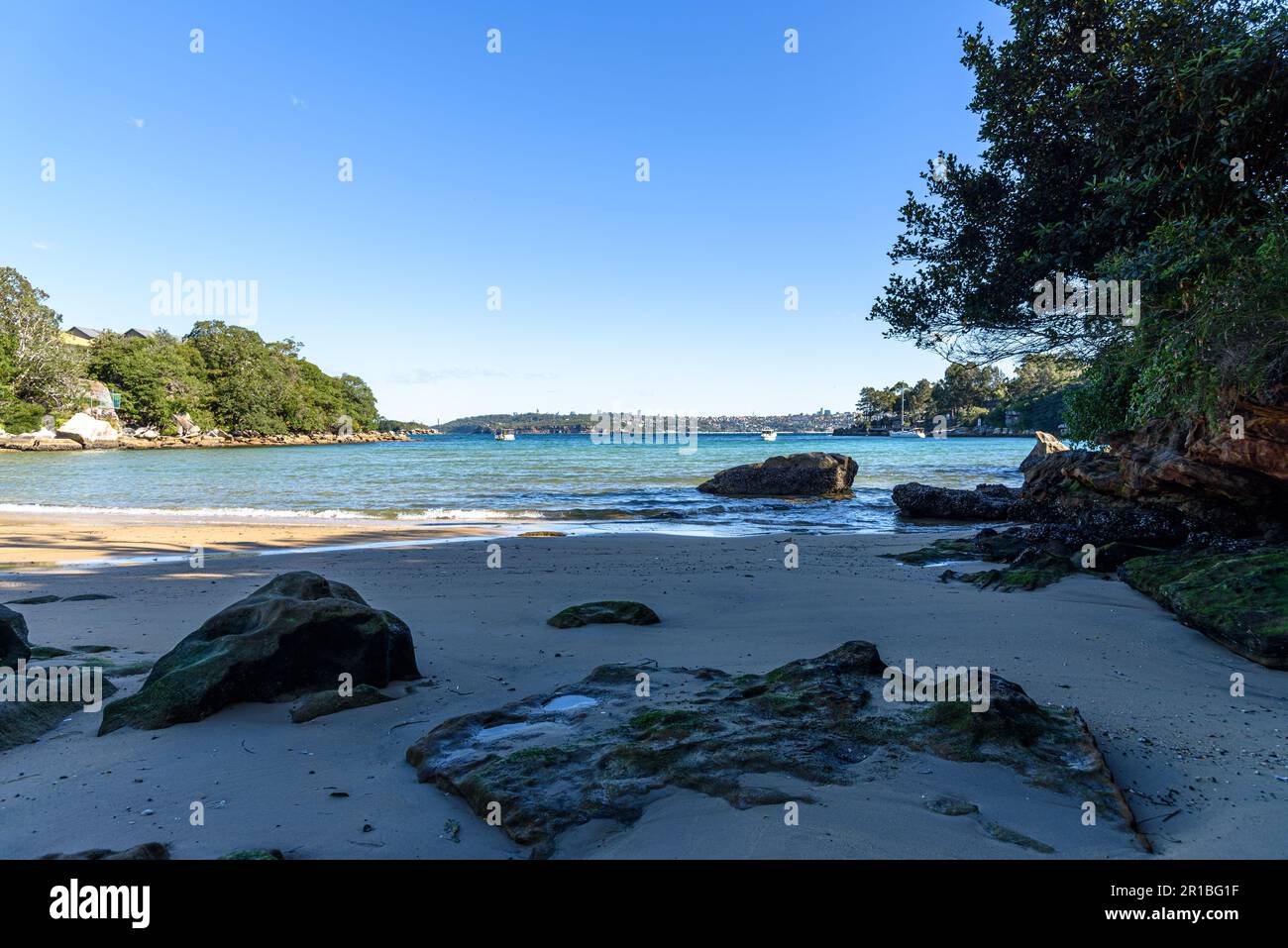 Rocks on the sand of Collins Beach in Manly, Sydney, looking out into ...