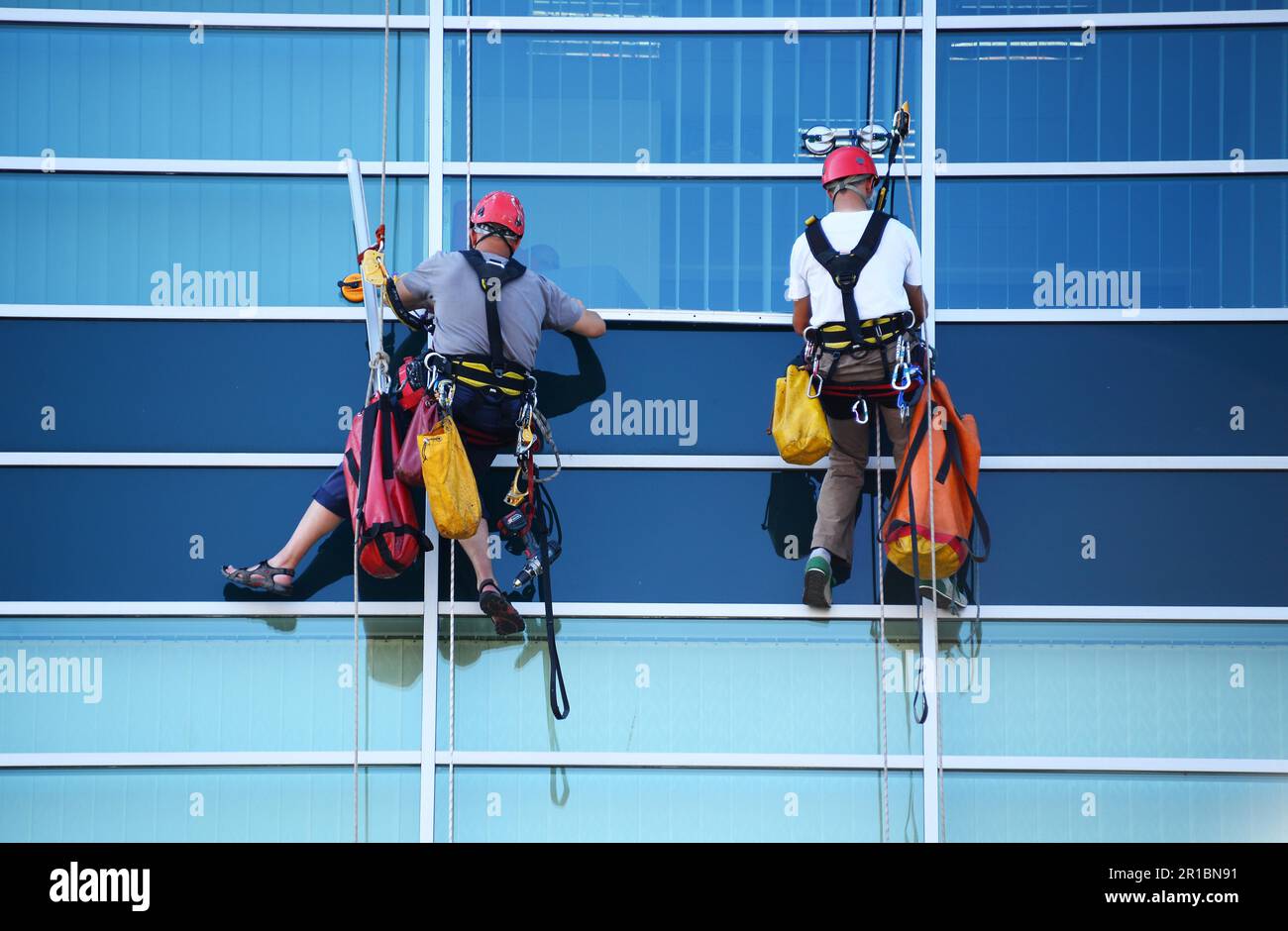 Two construction workers working at height on modern commercial ...
