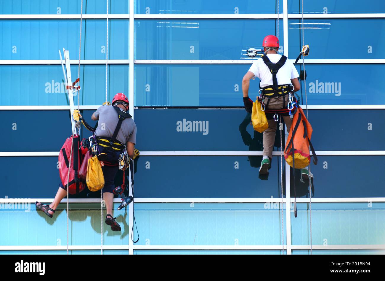 Two construction workers working at height on modern commercial ...