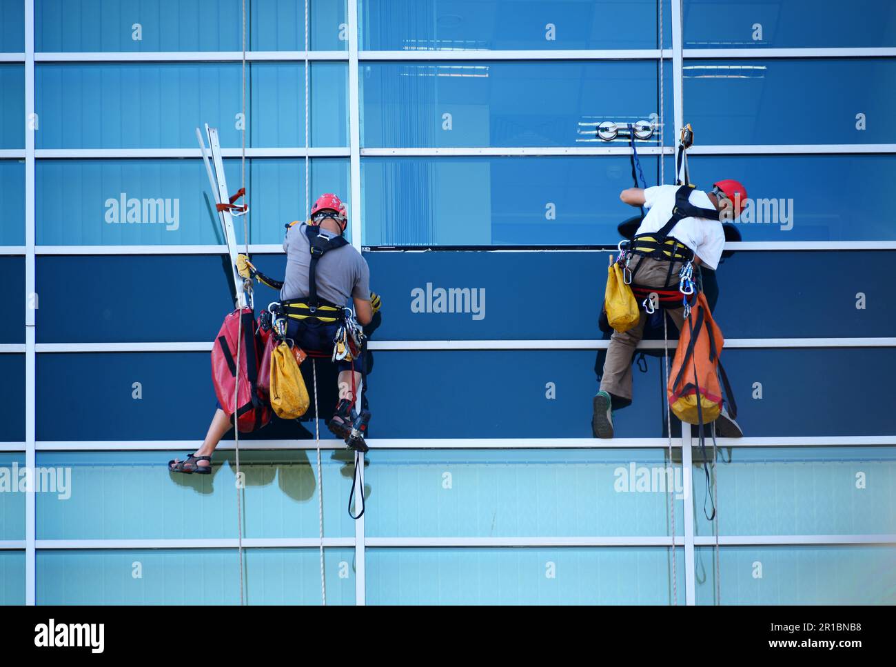 Two construction workers working at height on modern commercial ...