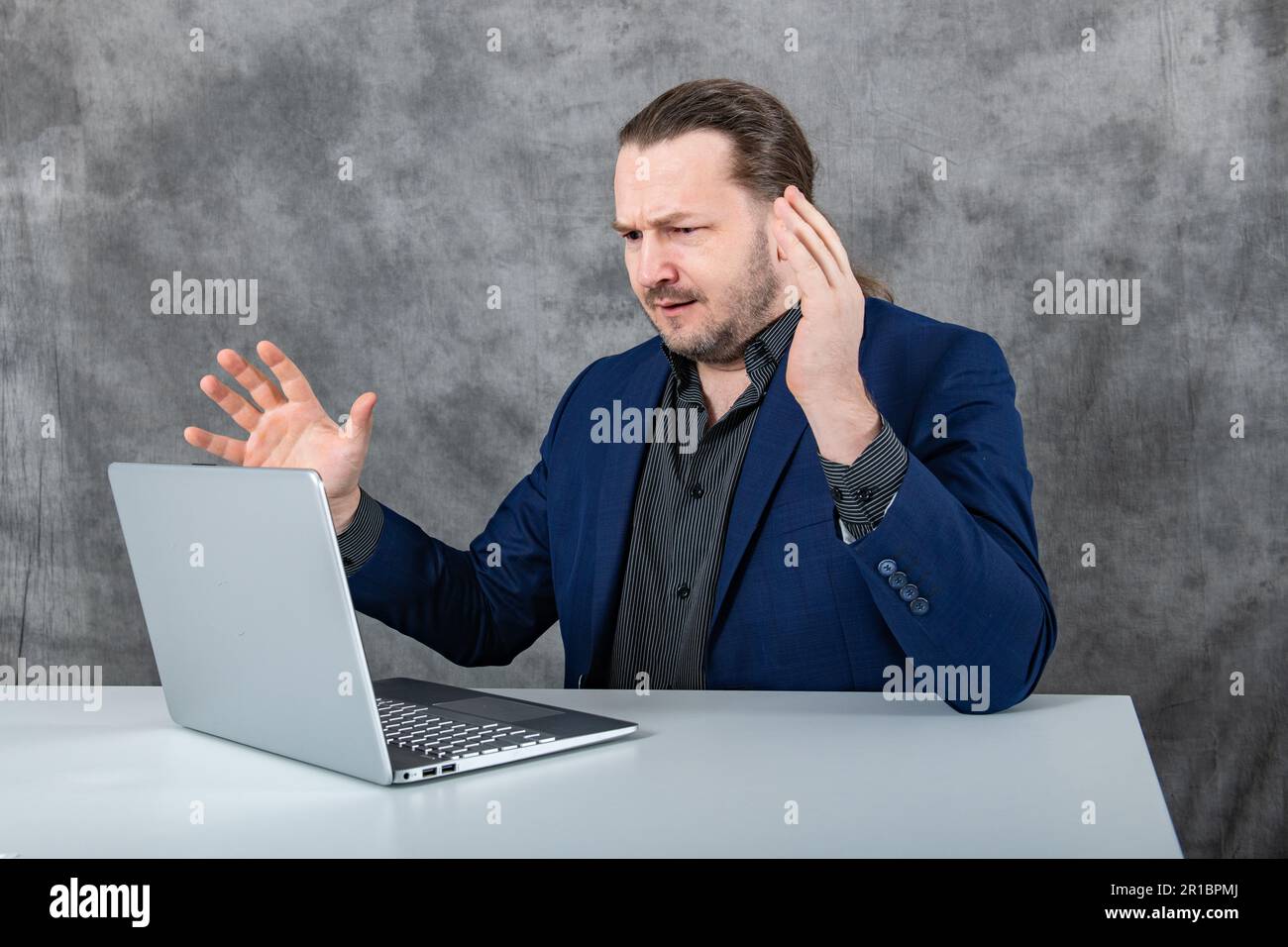 Angry man working on laptop in blue suit Stock Photo - Alamy