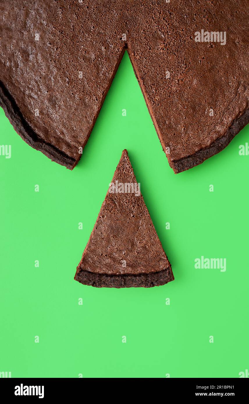 Top view with slice of chocolate pie minimalist on a green table ...