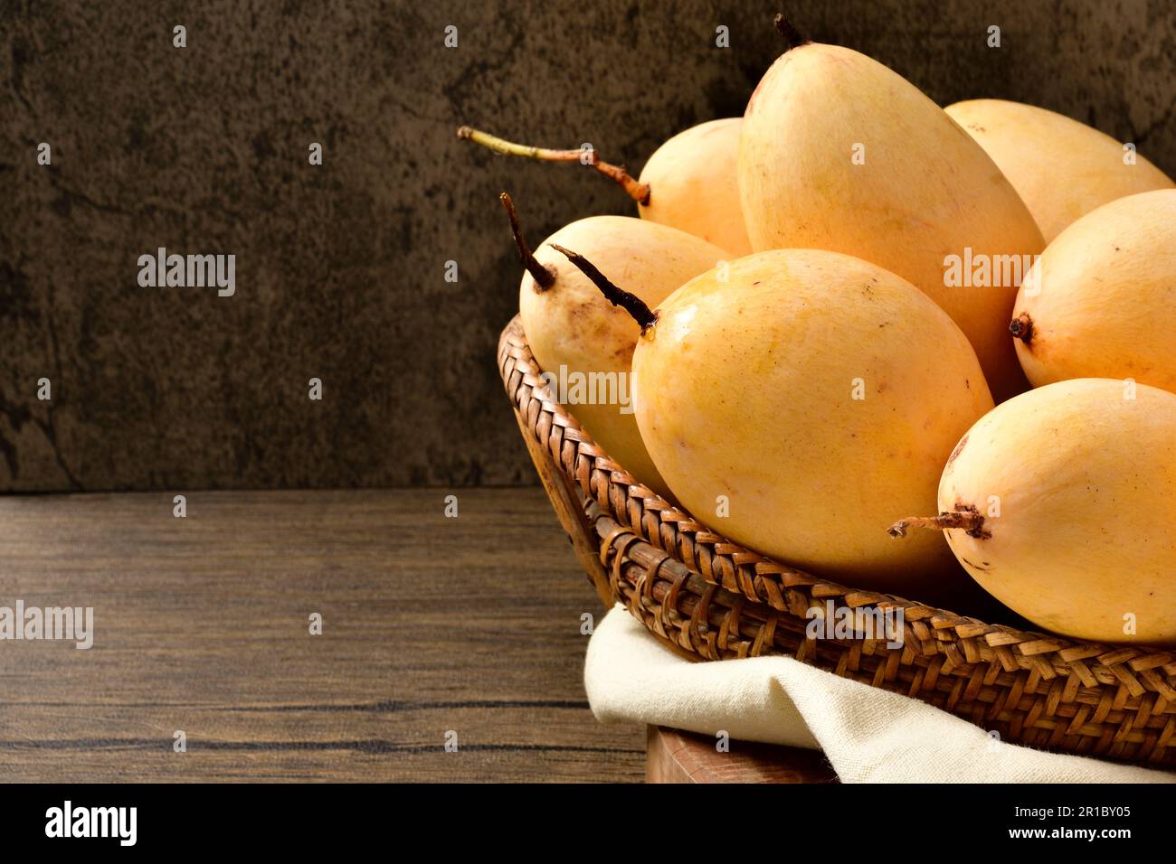 Thai mangos in wicker baskets on wooden table and dark background ...