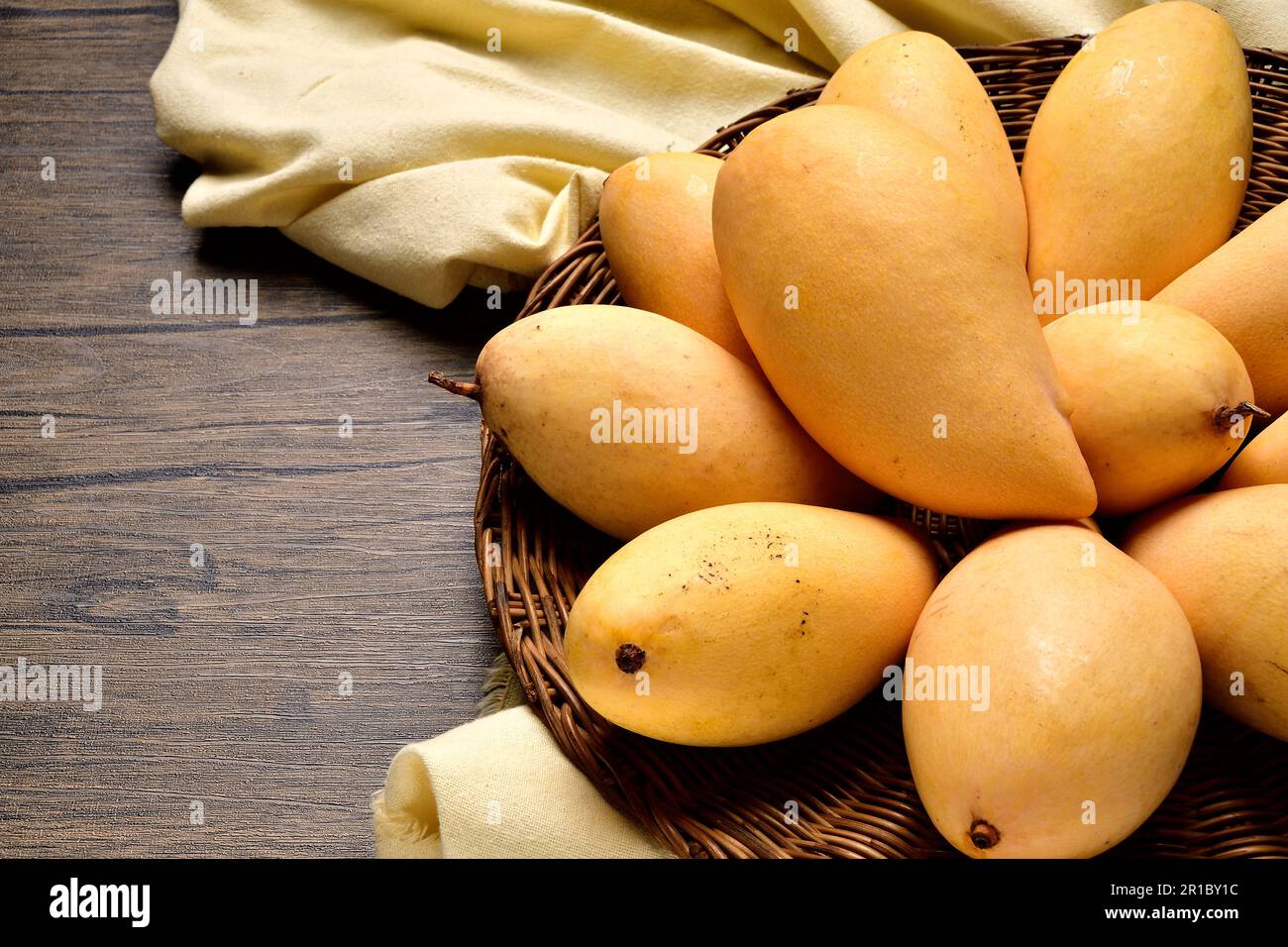 Top Views Many mangoes in wicker basket on wooden table background.Thai ...