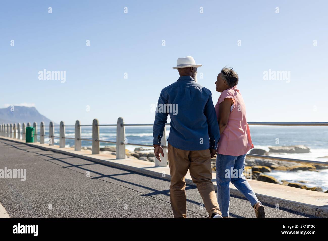 Happy senior african american couple with sun hat walking on promenade ...