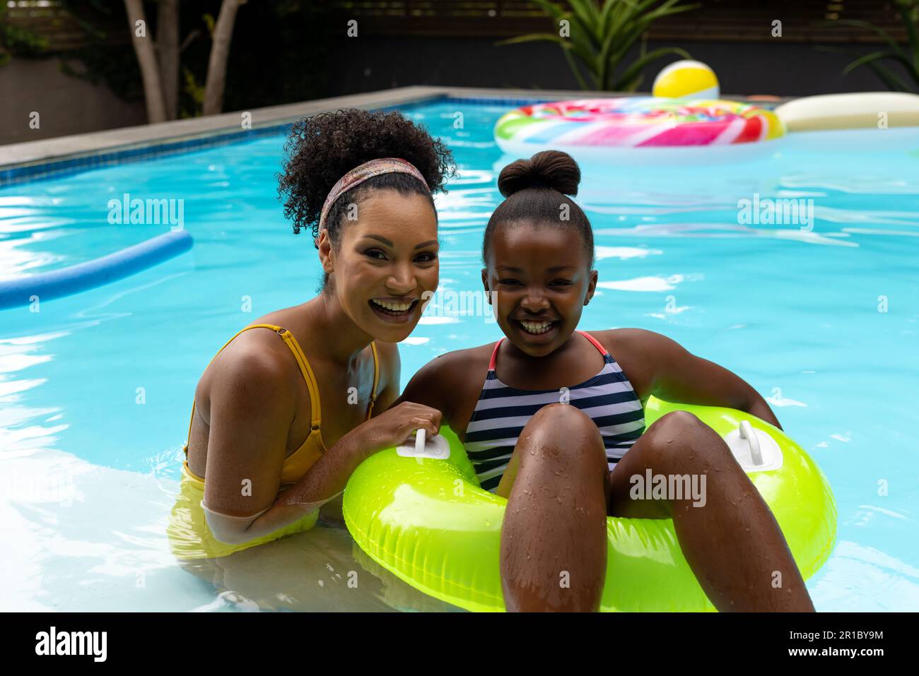 Portrait of happy african american mother and daughter on inflatable in ...