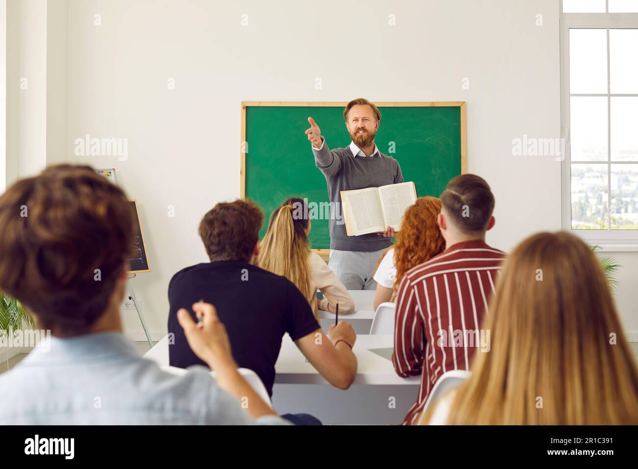 Middle aged professor lector is showing on student in class for answer ...