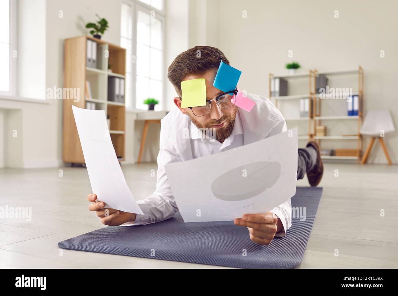 Funny man with sticky notes on face multitasking, working with papers ...