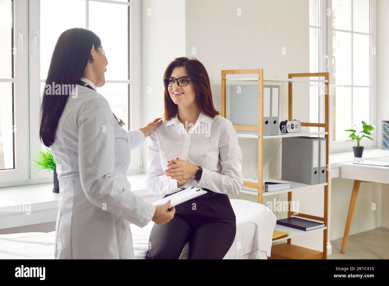 Smiling caring female doctor comforting patient in office Stock Photo ...