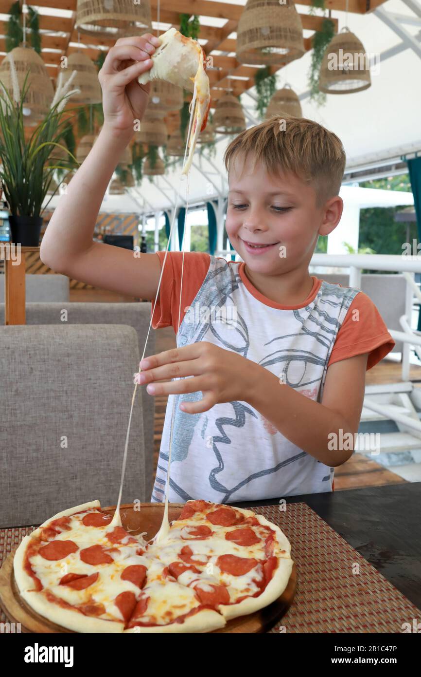 Boy eating pepperoni pizza in a restaurant Stock Photo - Alamy