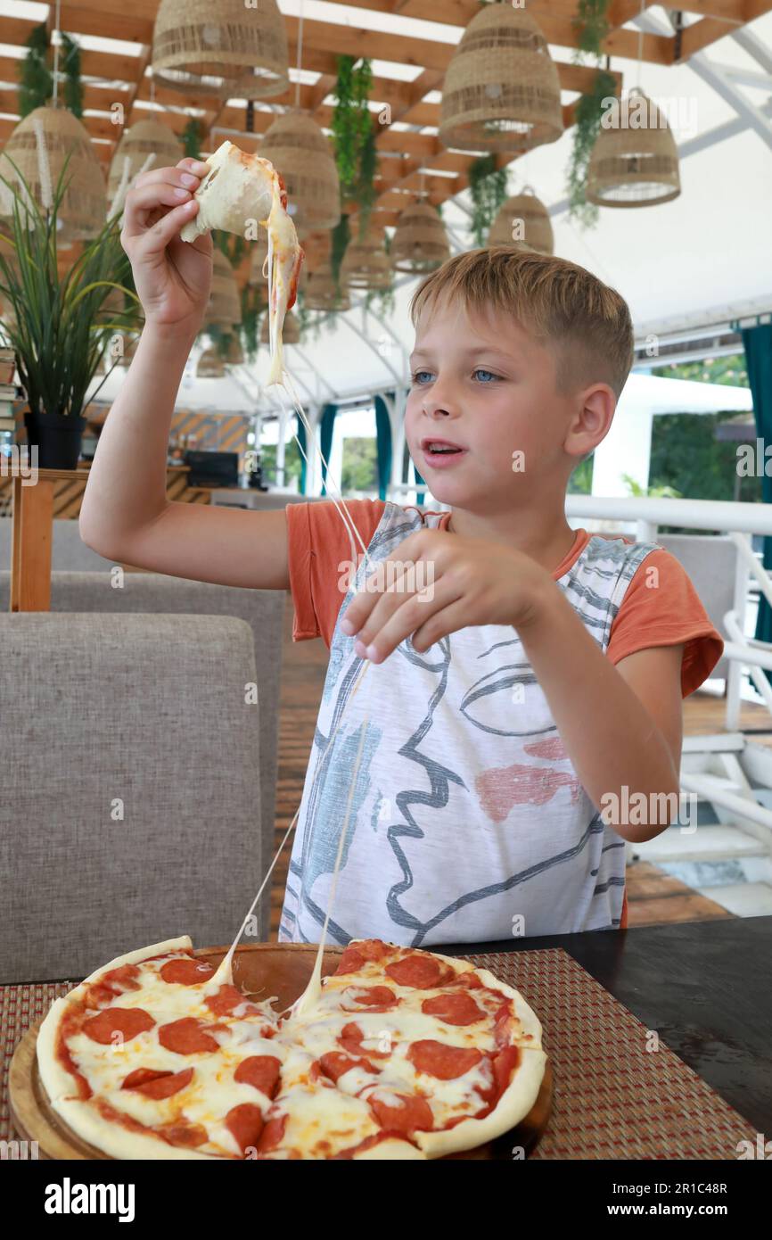 Kid eating pepperoni pizza in a restaurant Stock Photo - Alamy