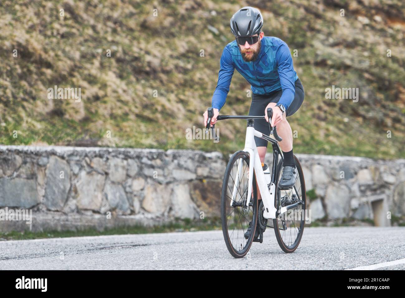 Man cyclist climbs asphalt road Stock Photo - Alamy