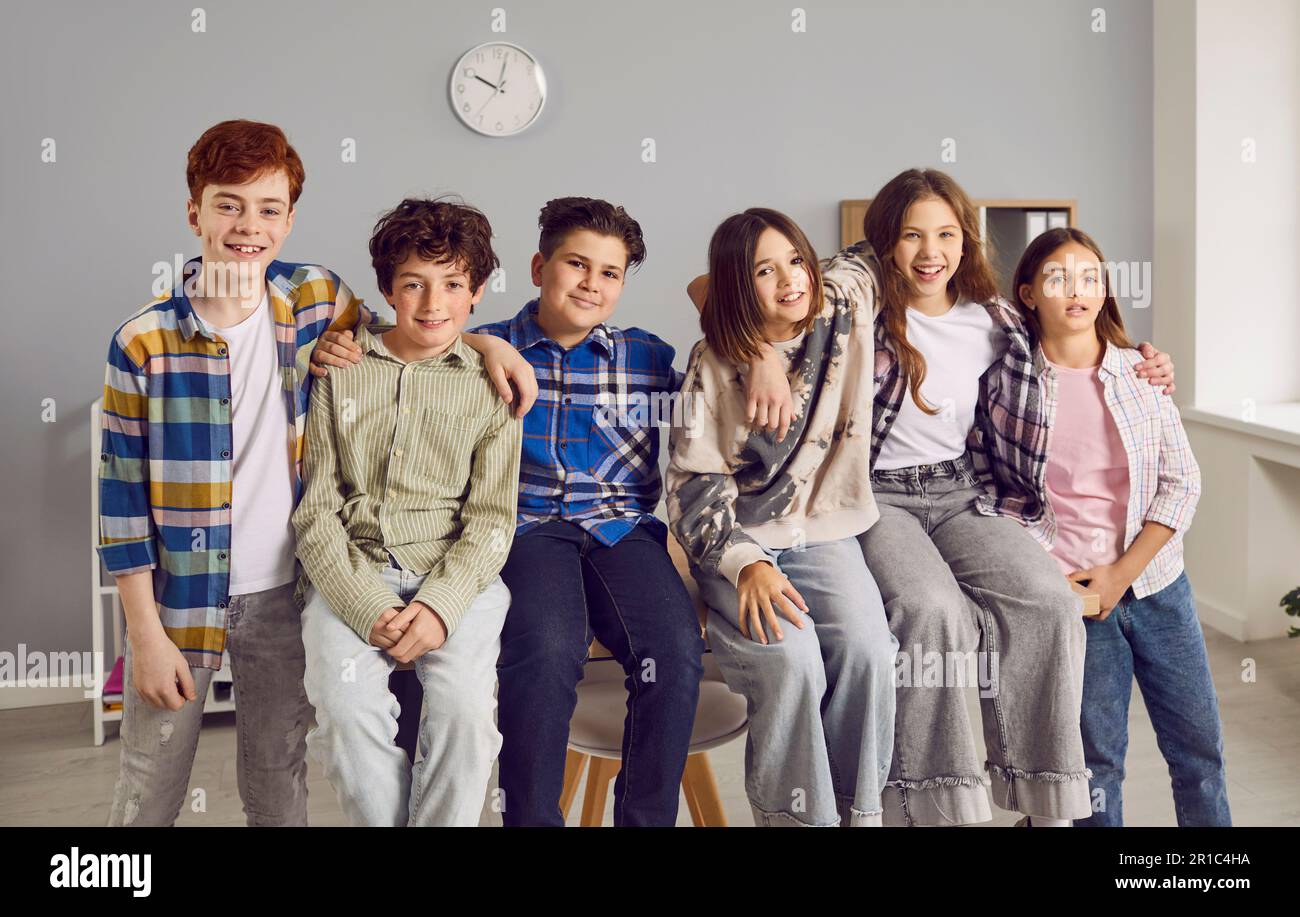 Group portrait of happy classmates and friends sitting on a table in ...