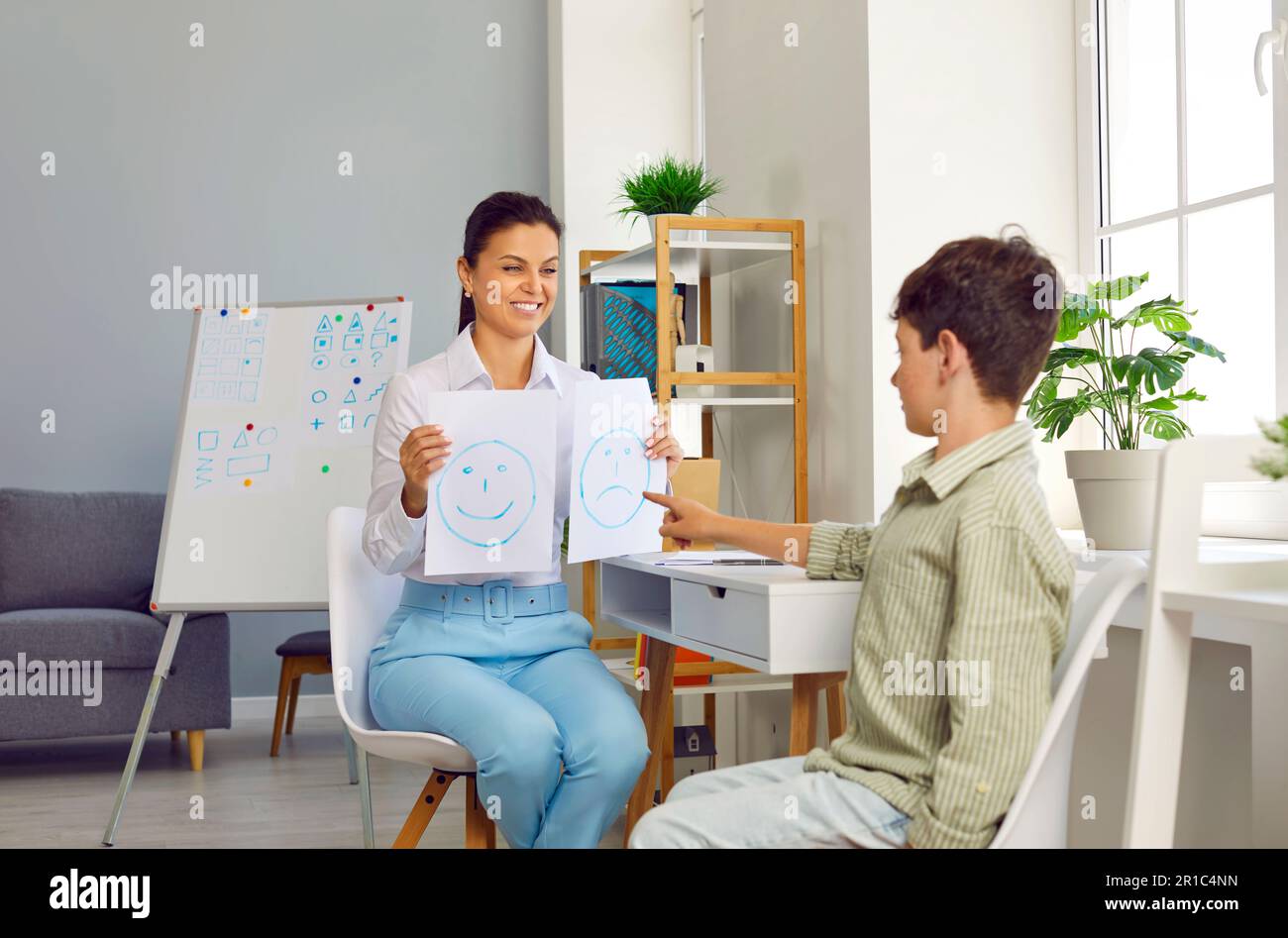 Woman psychologist showing cards with sad and happy emoticons to teen ...