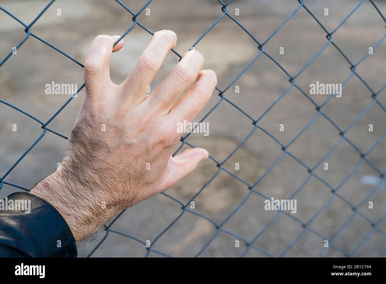 Hand on a metal fence. Border, prison, illegal migration concept. High ...