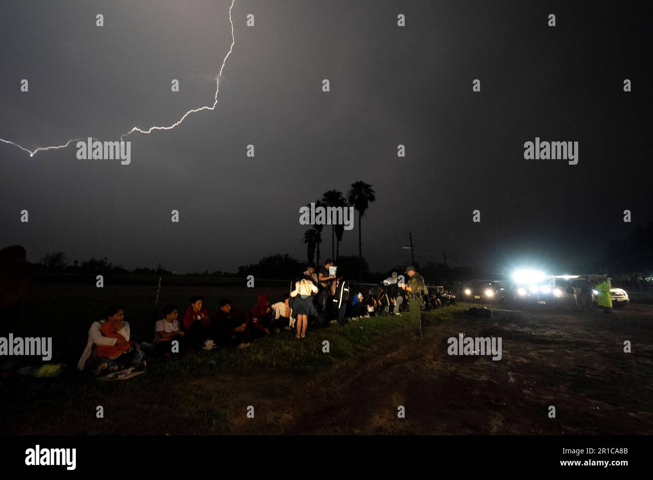 A lightning bolt is seen in the sky during a storm as migrants are ...