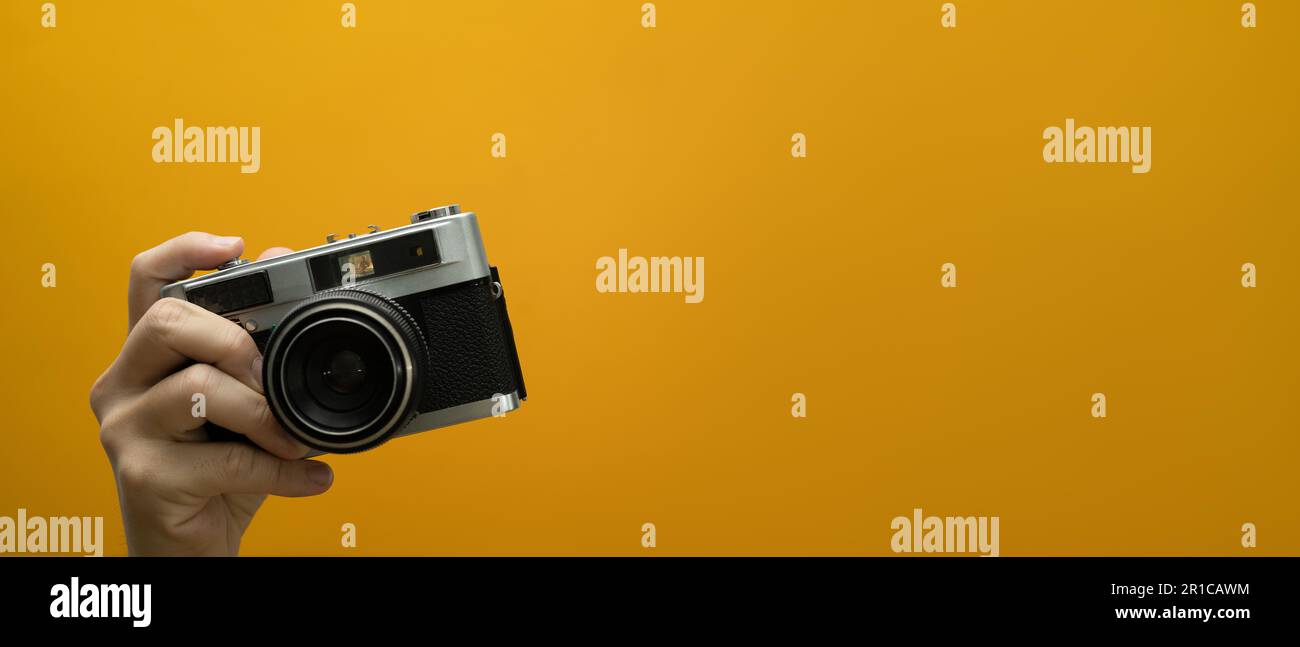 Image of hand holding vintage camera isolated on yellow background ...