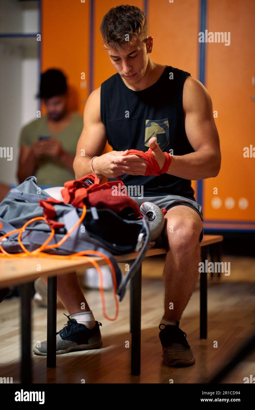 Young handsome man in locker room, getting ready for workout, tying ...