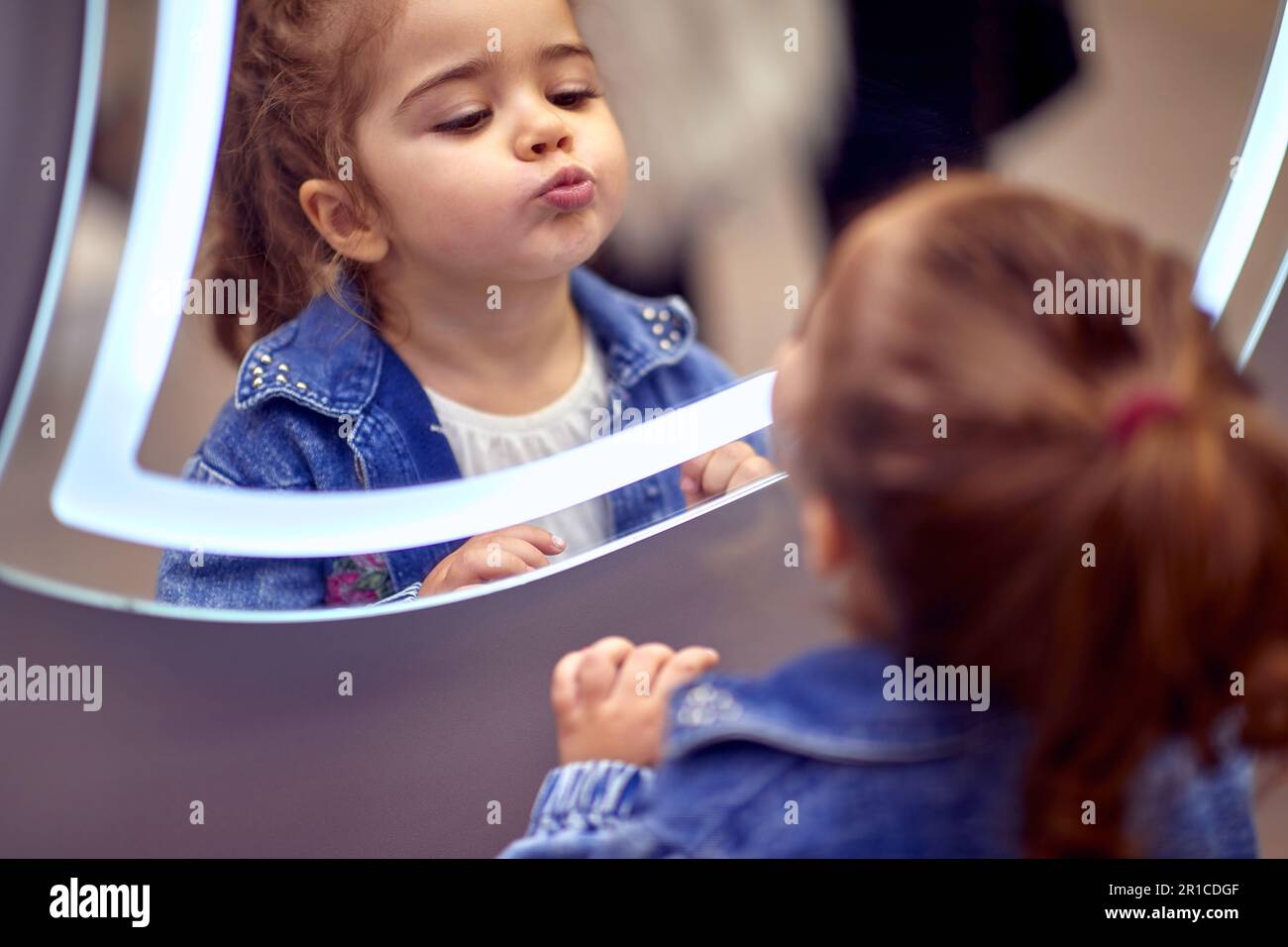 Little girl who is playing with her reflection in the mirror Stock ...