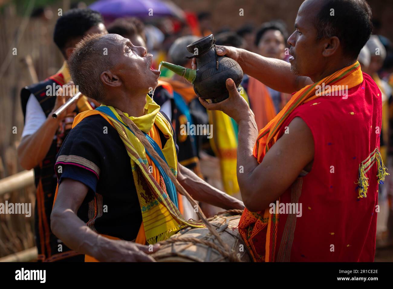 A Tiwa tribal man in traditional attire pours rice beer into the mouth ...