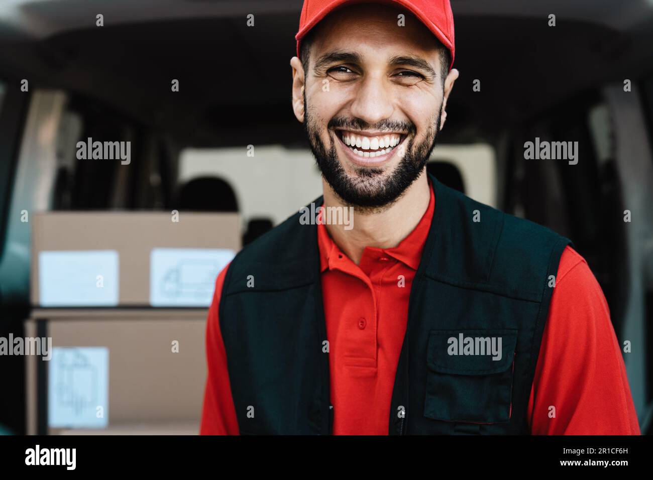 Young courier delivery man smiling into the camera while standing in ...