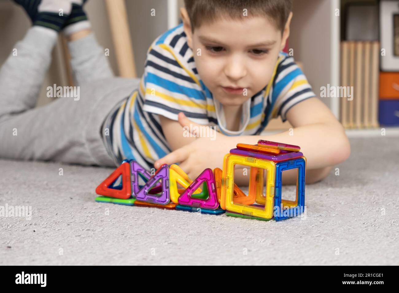 A cute 5 year old boy creates figures with a magnetic construction kit ...