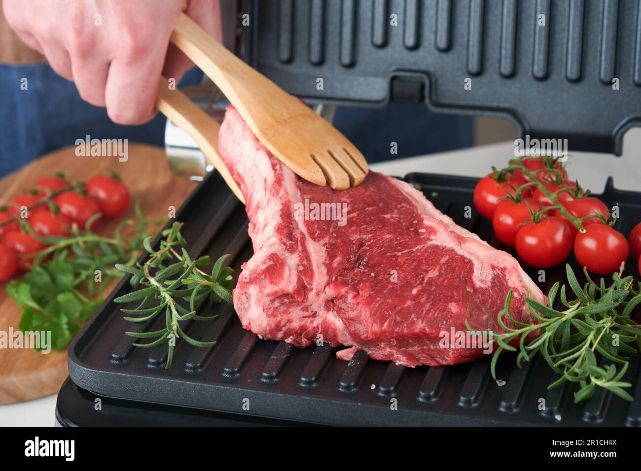 Raw prime steaks on electric grill. Chef male hand holding steak Ribeye ...