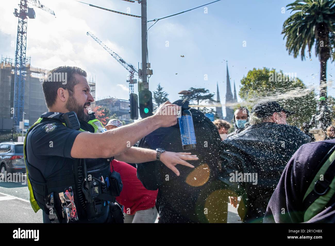 A police officer shouts get back as he deploys his crowd control spray ...