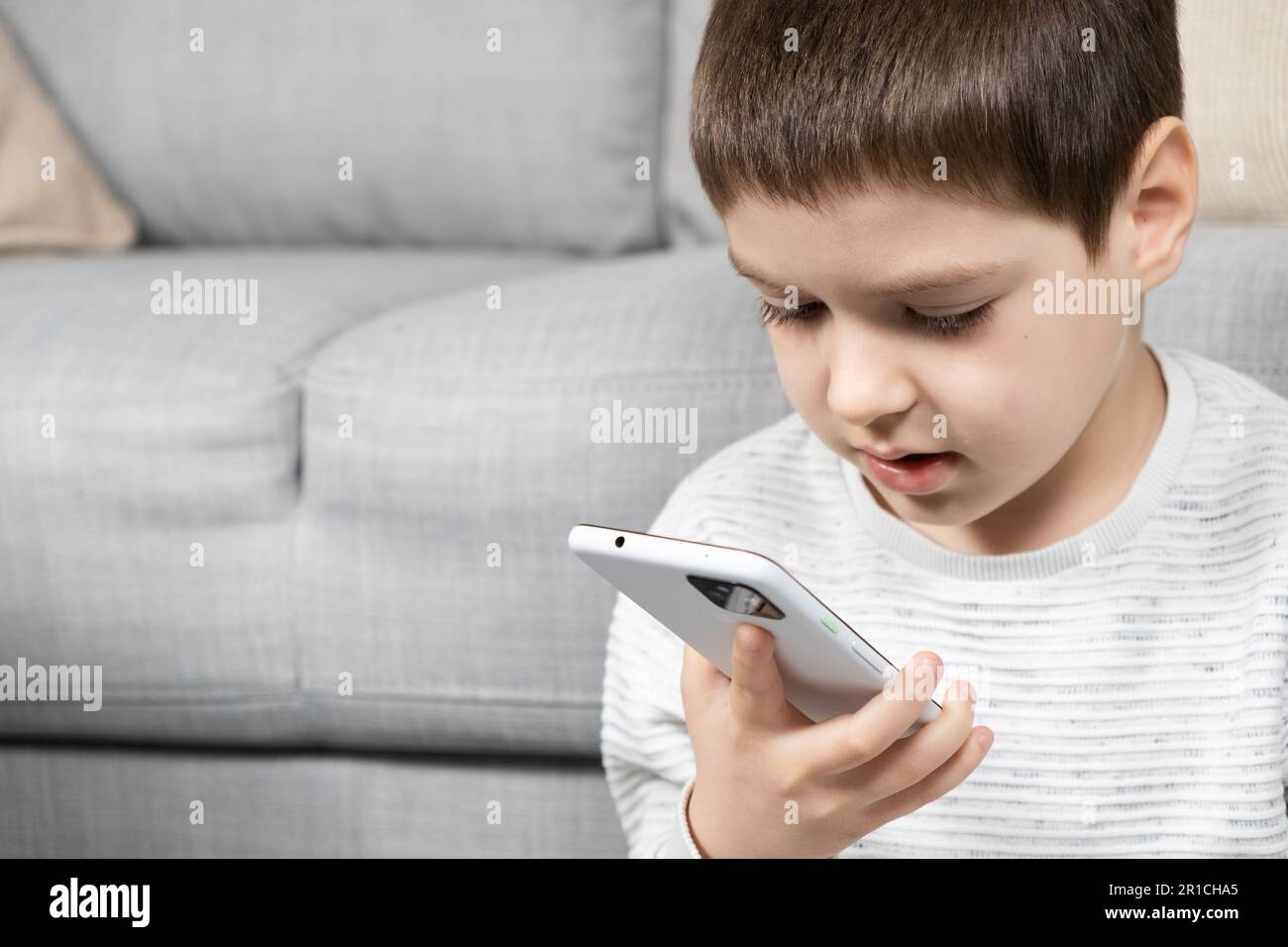 A preschool boy uses a smartphone, plays games on his phone, place for ...