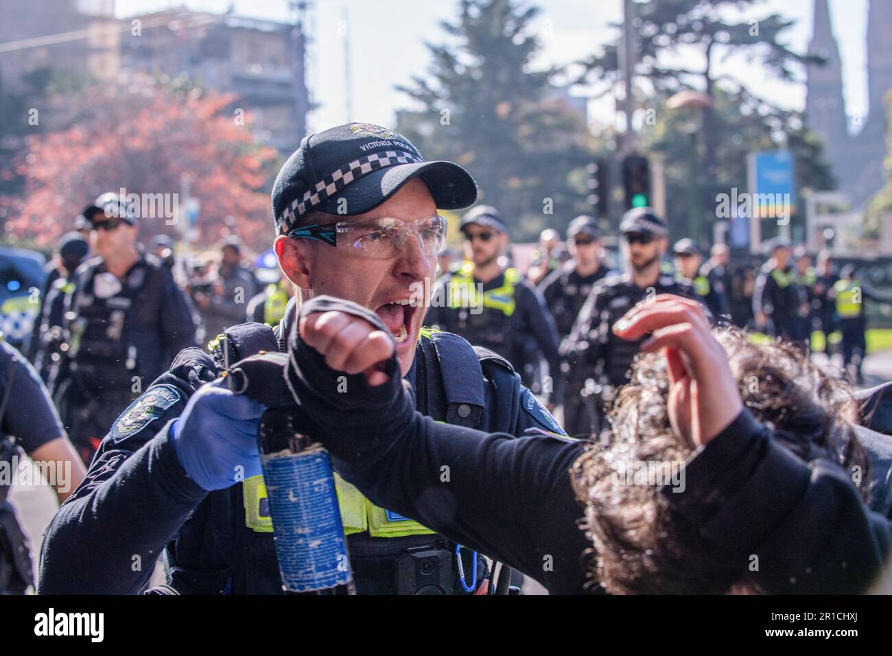 A police officer shouts get back as he deploys his crowd control spray ...