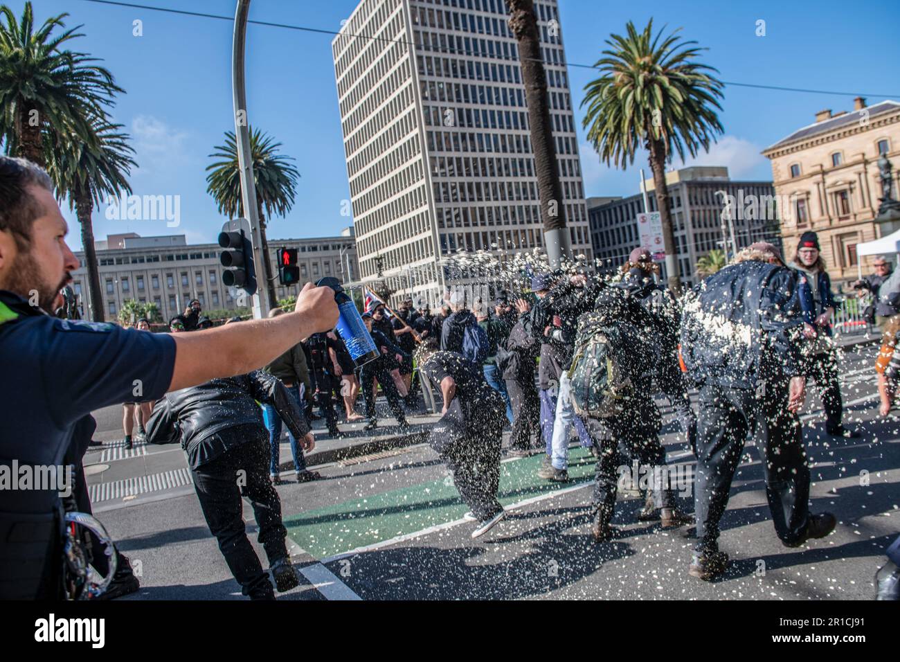 A police officer shouts get back as he deploys his crowd control spray ...