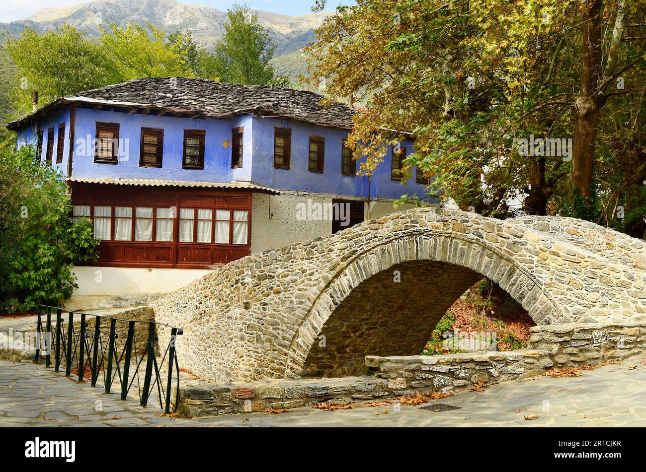 Greece, footbridge over river bed and colorful home in mountain village ...