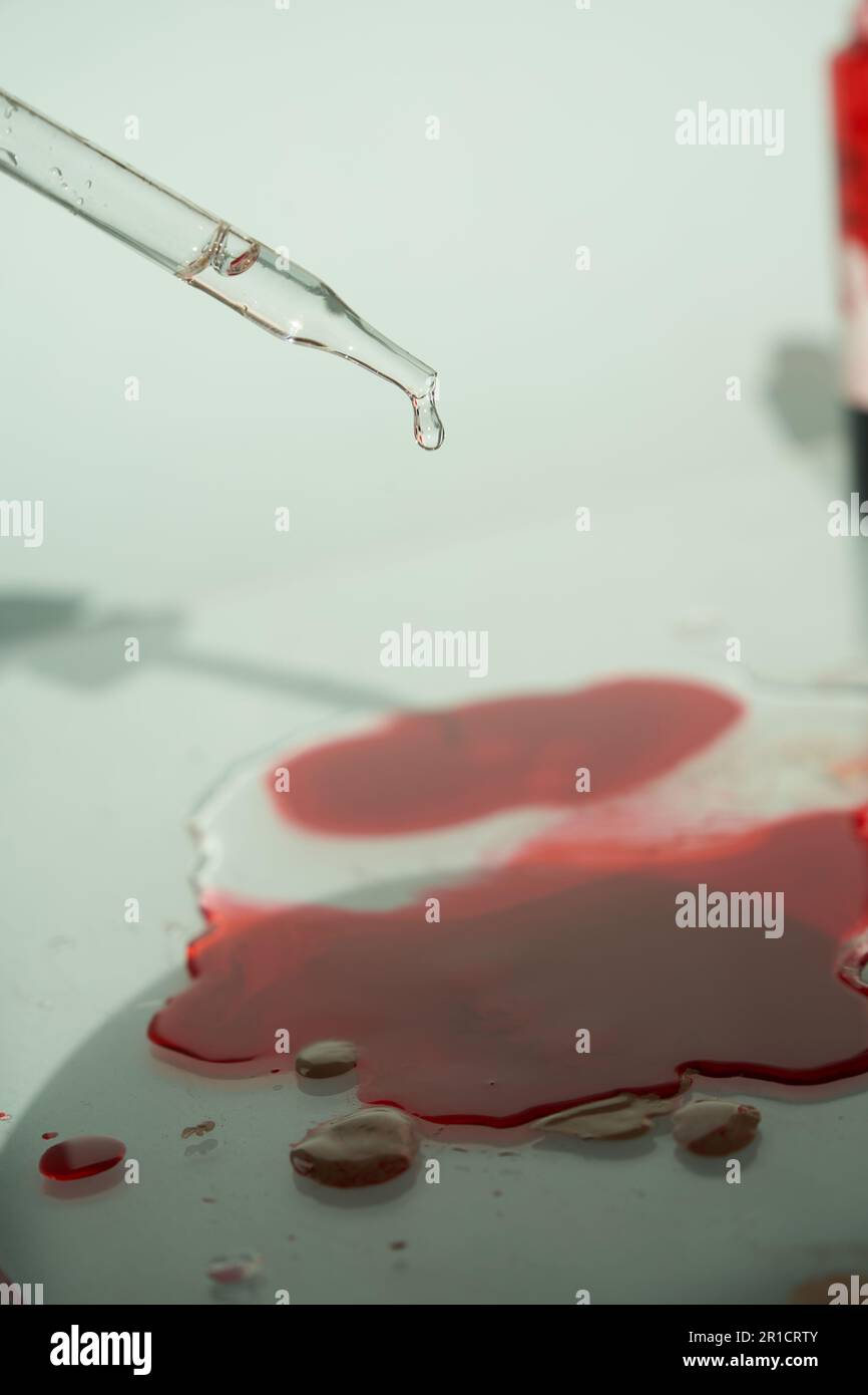 Red liquid with a pipette in the form of a spot on a light background ...