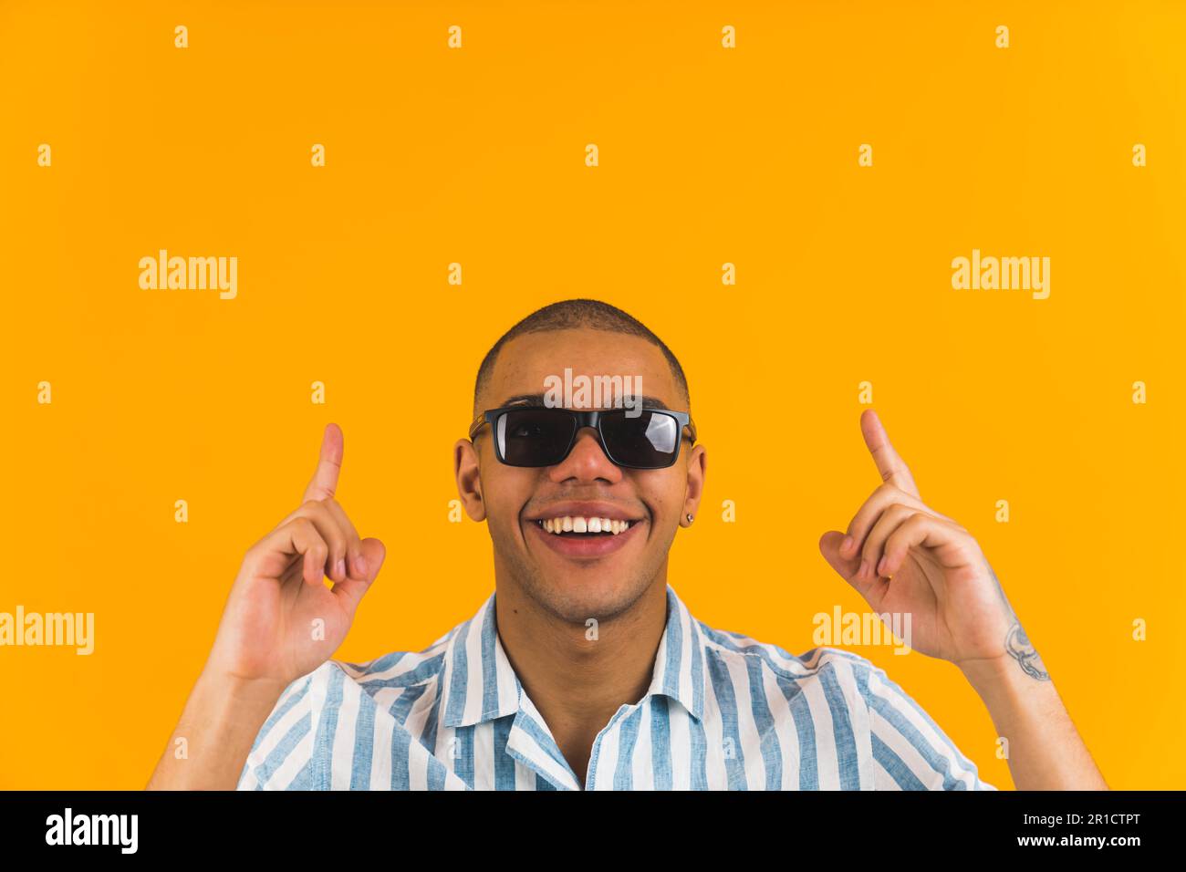 cheerful Afro-American boy with sunglasses pointing above himself on ...