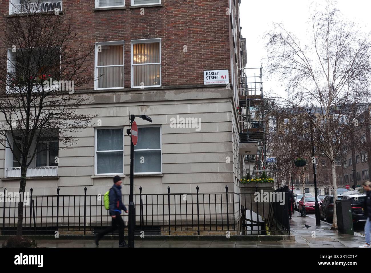 People walk past harley street london, UK street name plate on wall ...