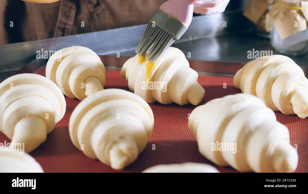 The baker coats the raw dough with the yolk, using a brush for a nice shell Stock Photo - Alamy
