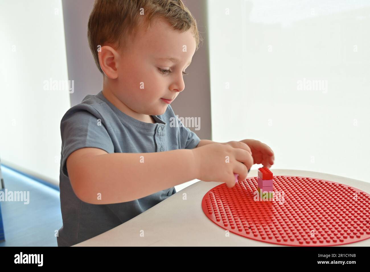 Little child playing with lots of colorful plastic toys indoor ...