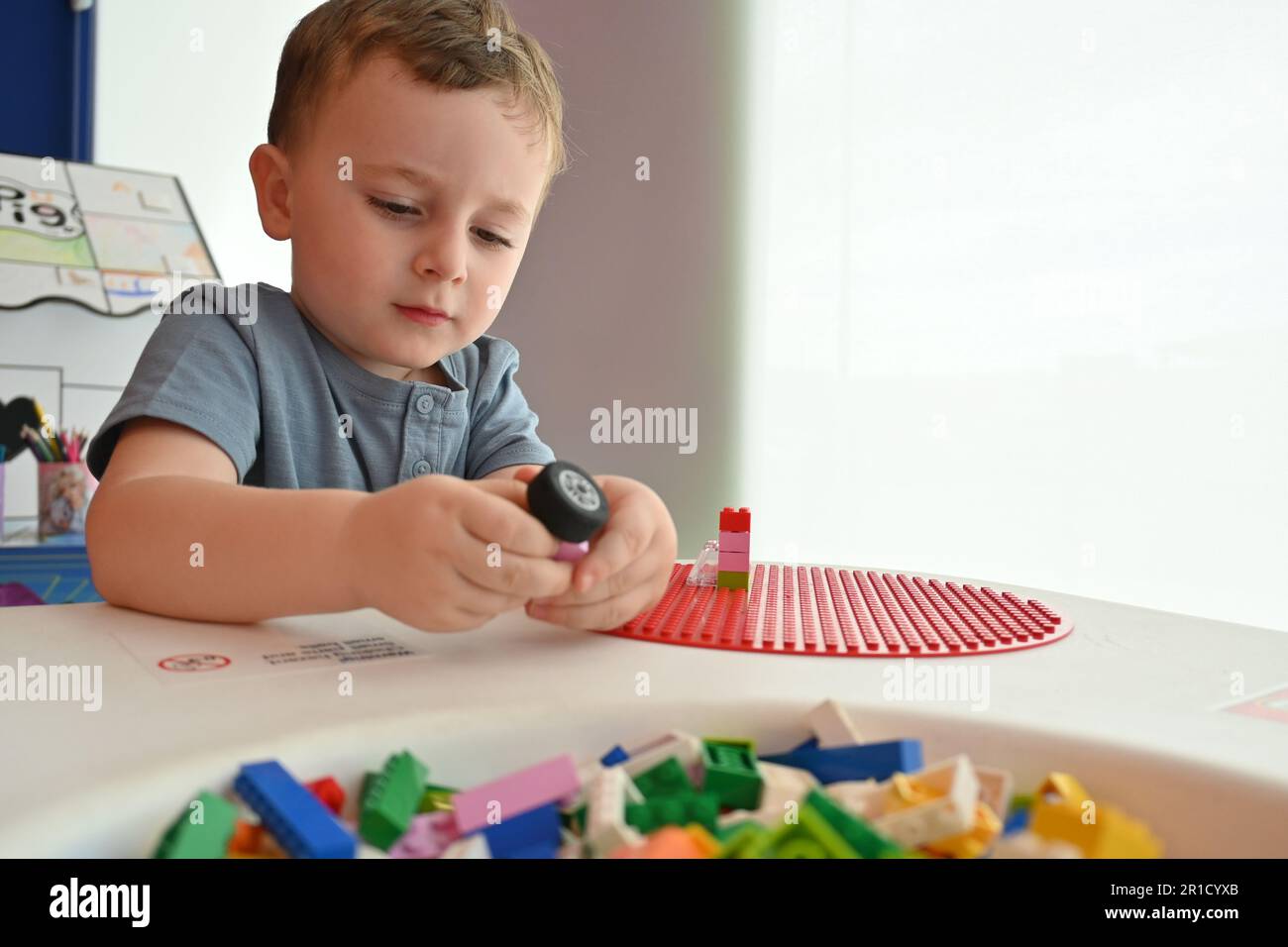 Little child playing with lots of colorful plastic toys indoor ...