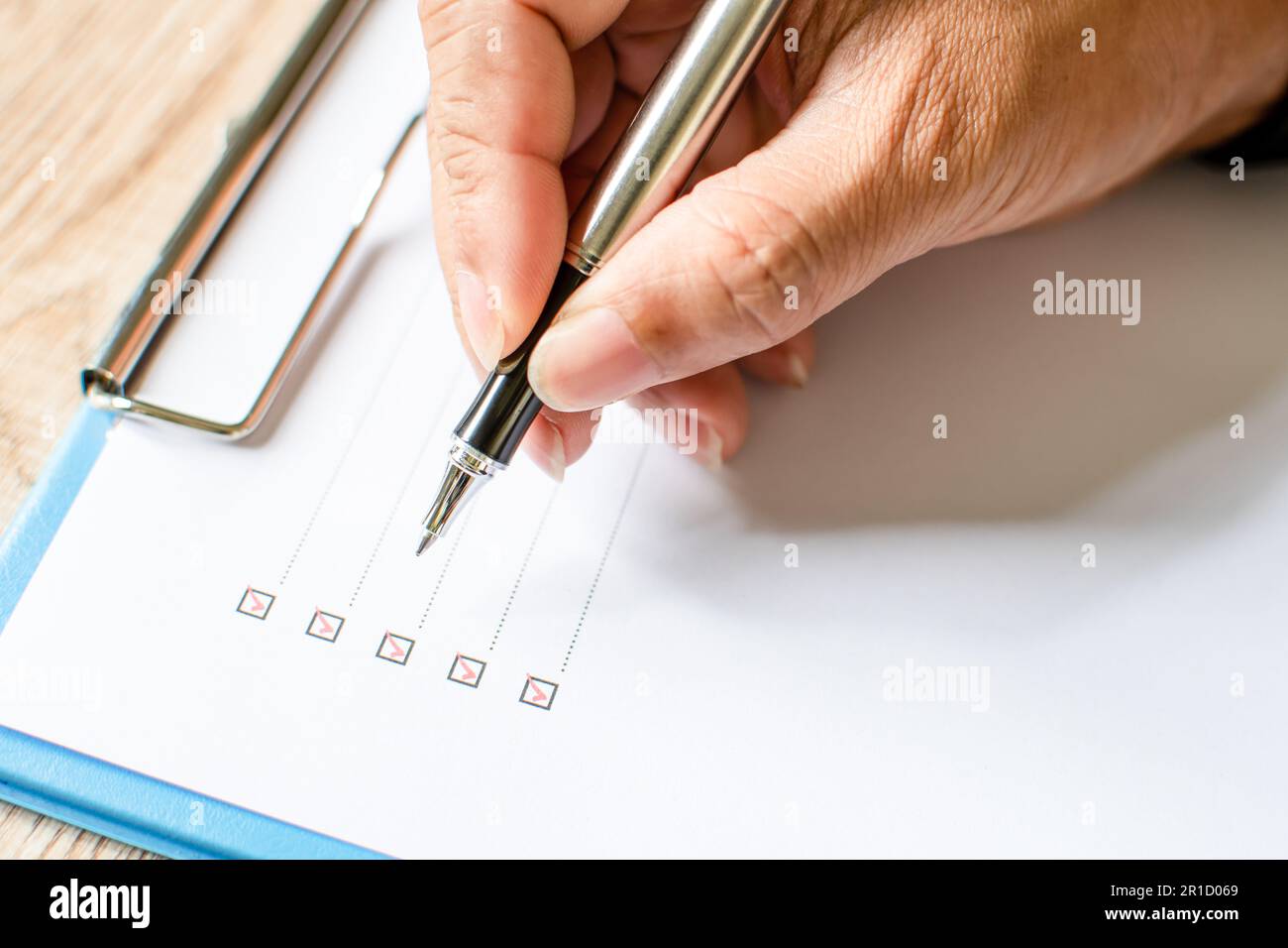 Close- up, Men's fingers holding pen writing on checklist paper and the ...