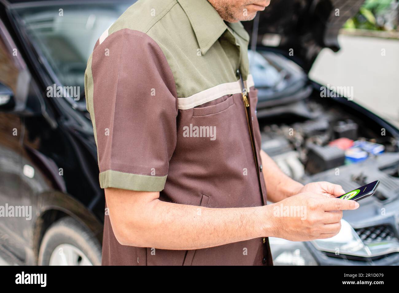 Technician holds smartphone to watch the battery function monitor. Mobile device screen show ...
