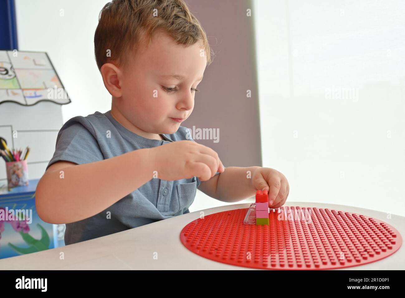 Little child playing with lots of colorful plastic toys indoor ...
